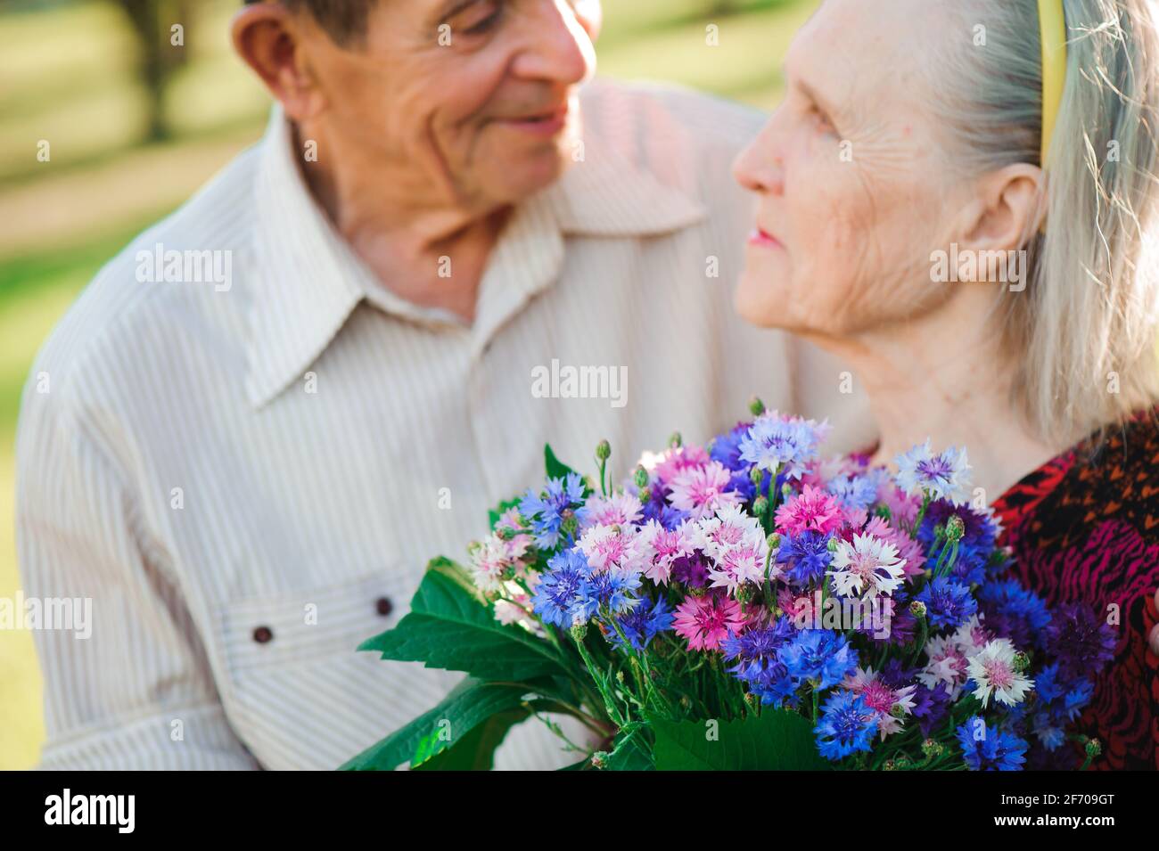 Flowers in hands for a beautiful elderly woman Stock Photo - Alamy
