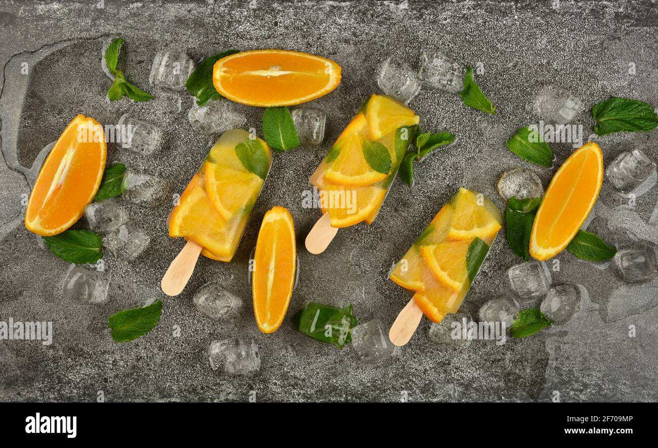 Close up three fruit ice cream popsicles with fresh orange slices ...