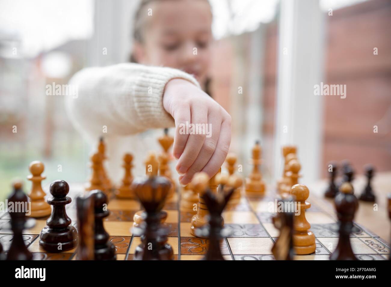 Beautiful cute genius child young girl playing chess with pieces on ...