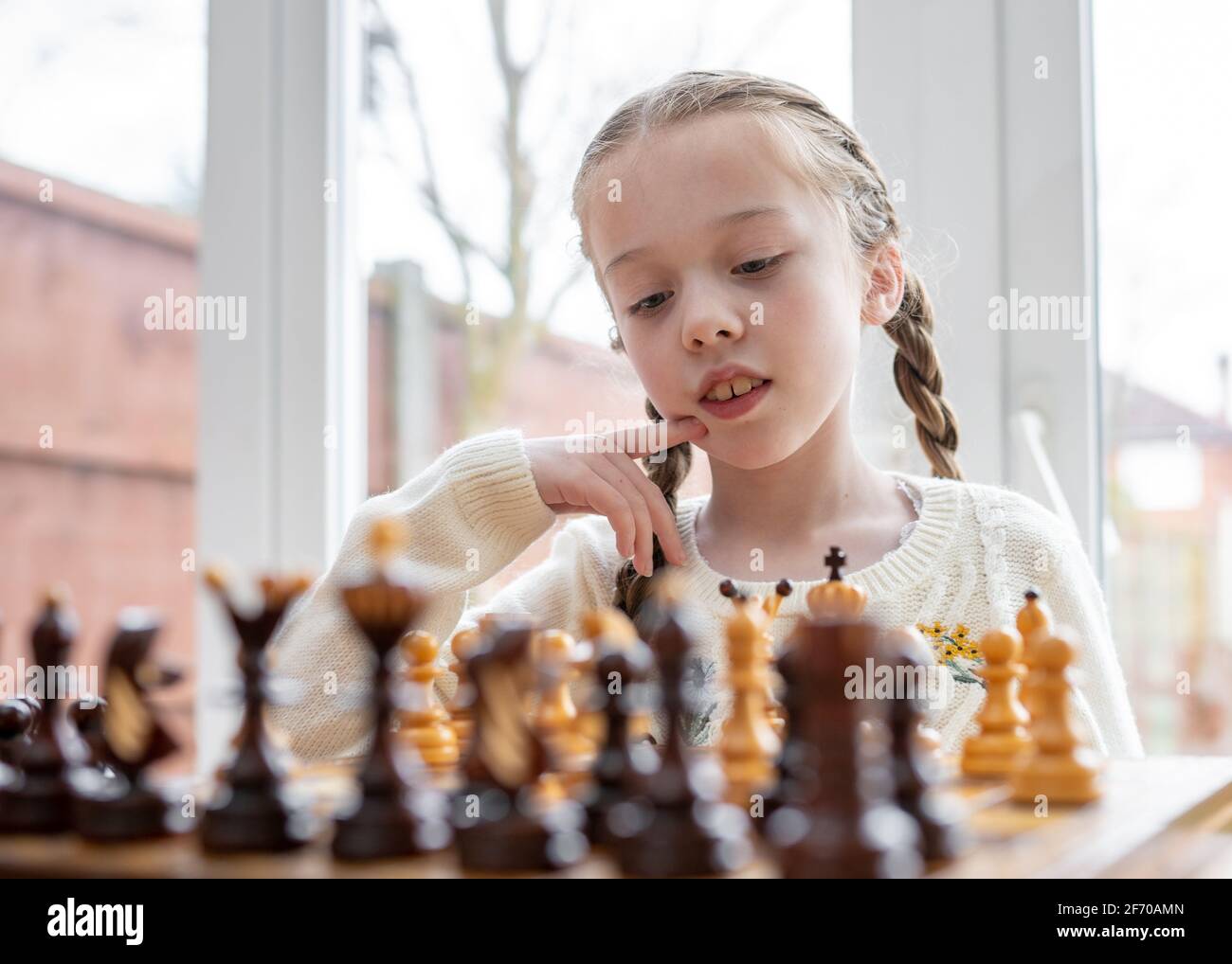 Beautiful cute genius child young girl playing chess with pieces on ...