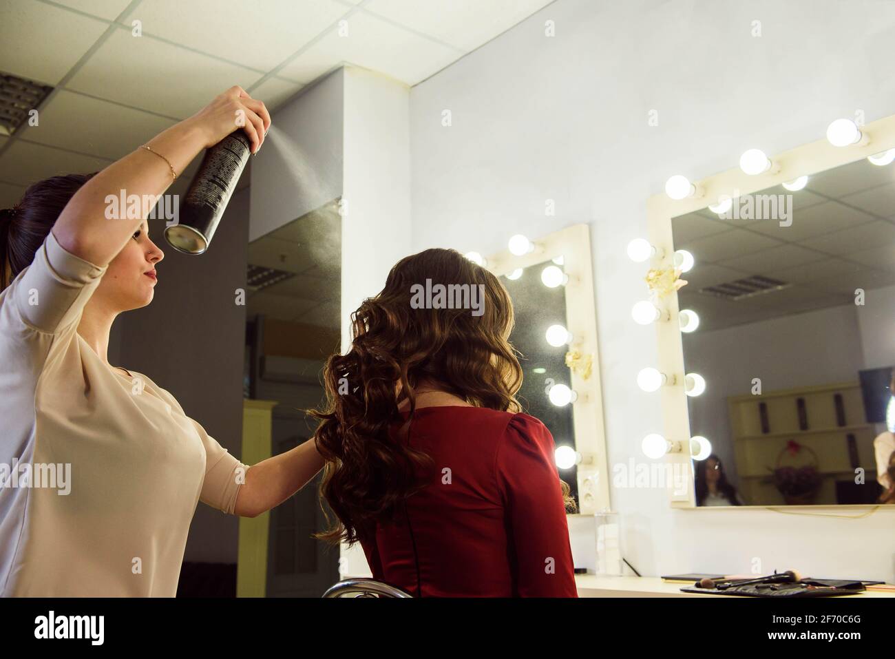 Master stylist makes model hairstyle using spray lacquer fixing Stock ...