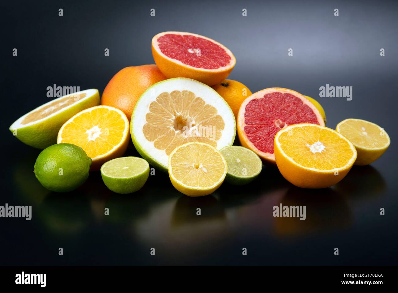 cut pieces of different citrus fruits on dark background Stock Photo ...