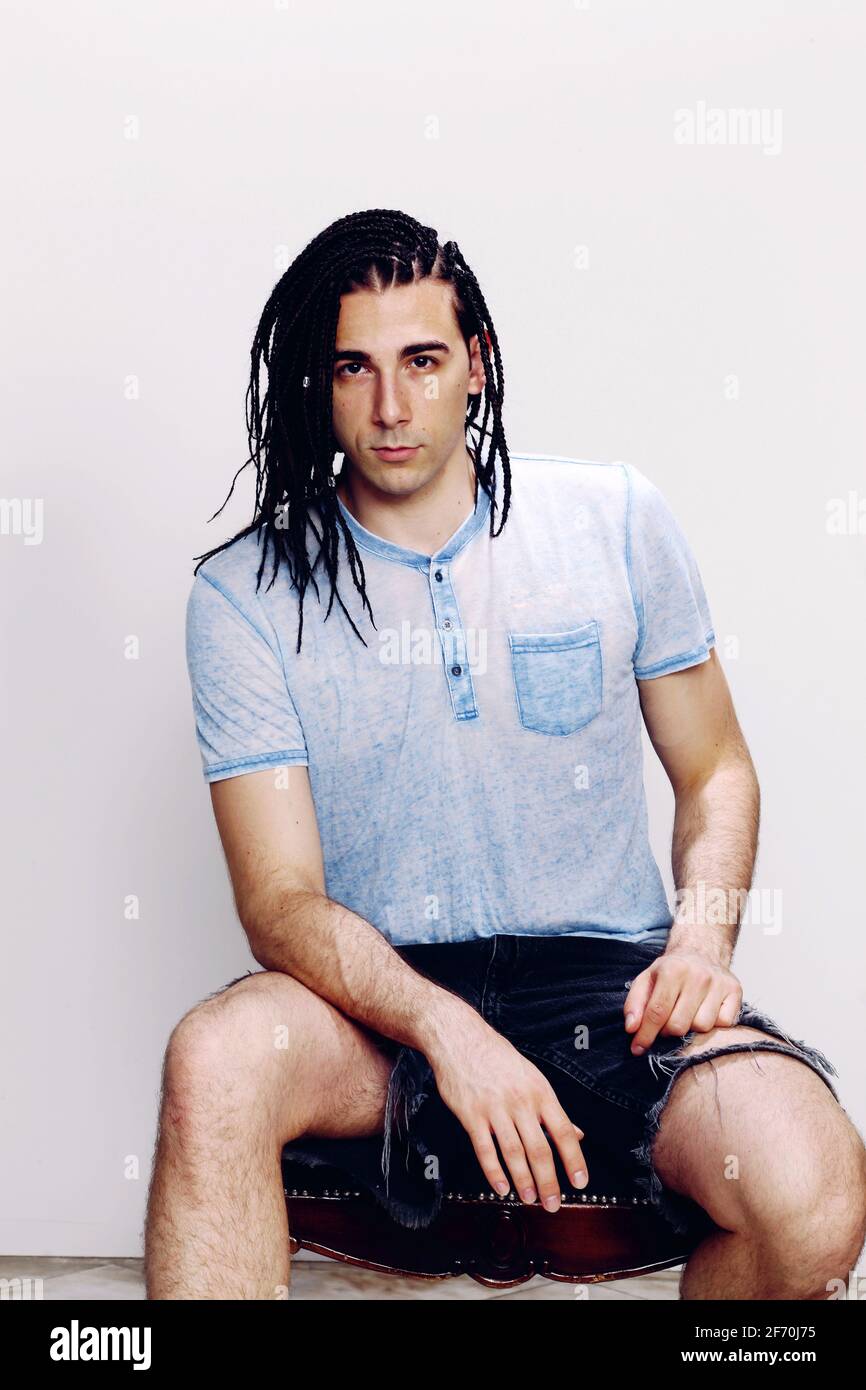 Stylish male model with afro braids posing in studio on isolated ...