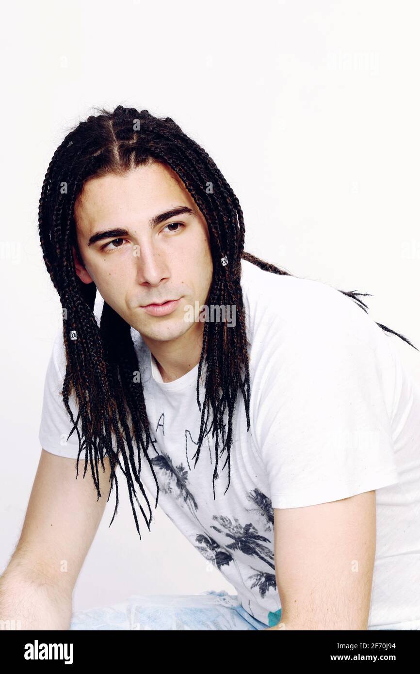 Stylish male model with afro braids posing in studio on isolated ...