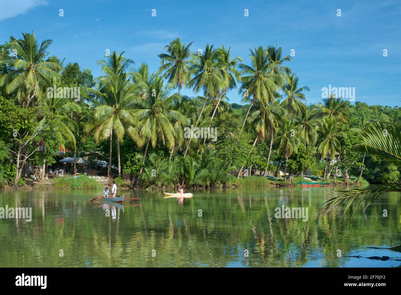 The Loboc River. A small outrigger boat ferries people across the river ...