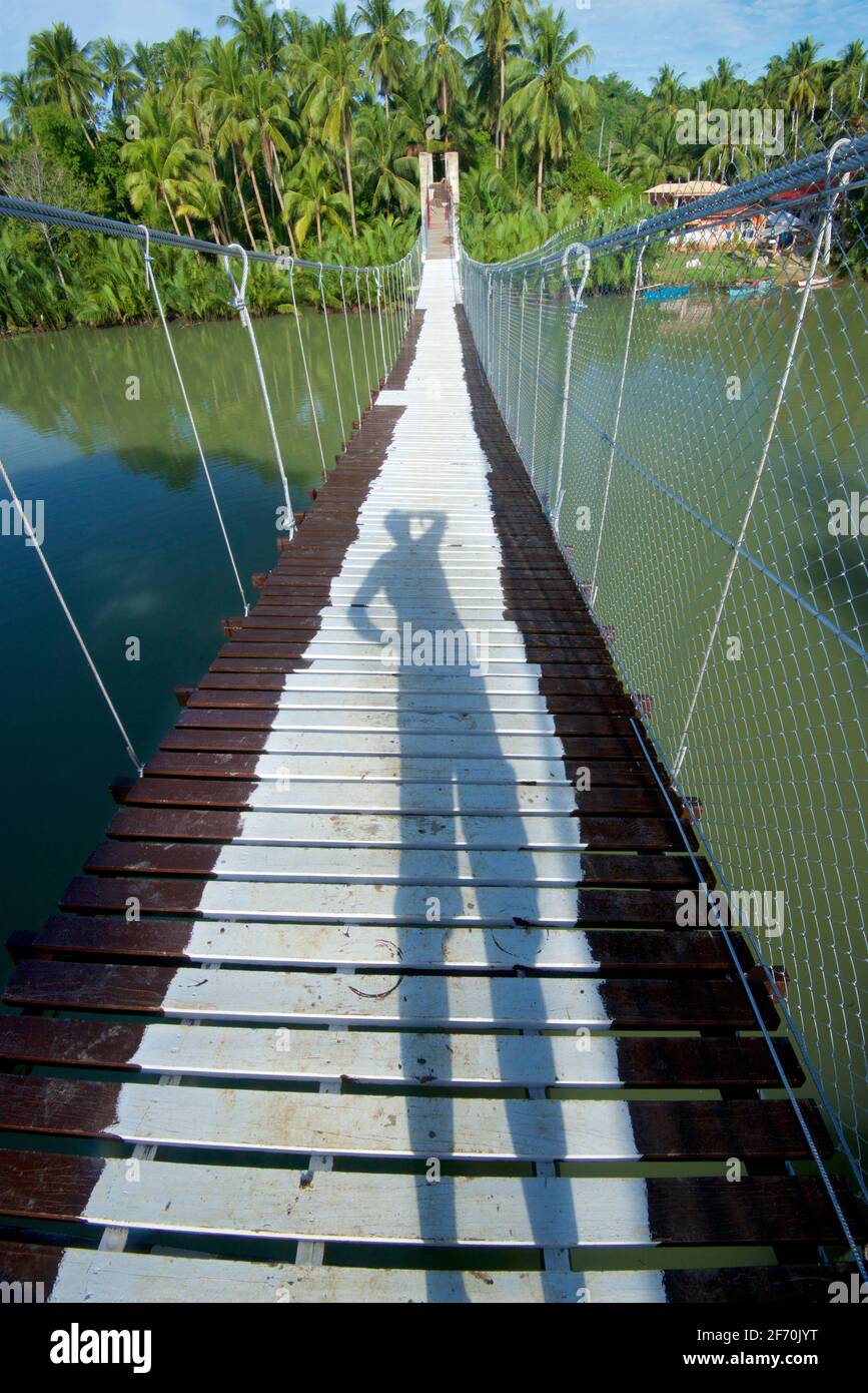 Pedestrian's shadow on a suspension footbridge over the Loboc River ...