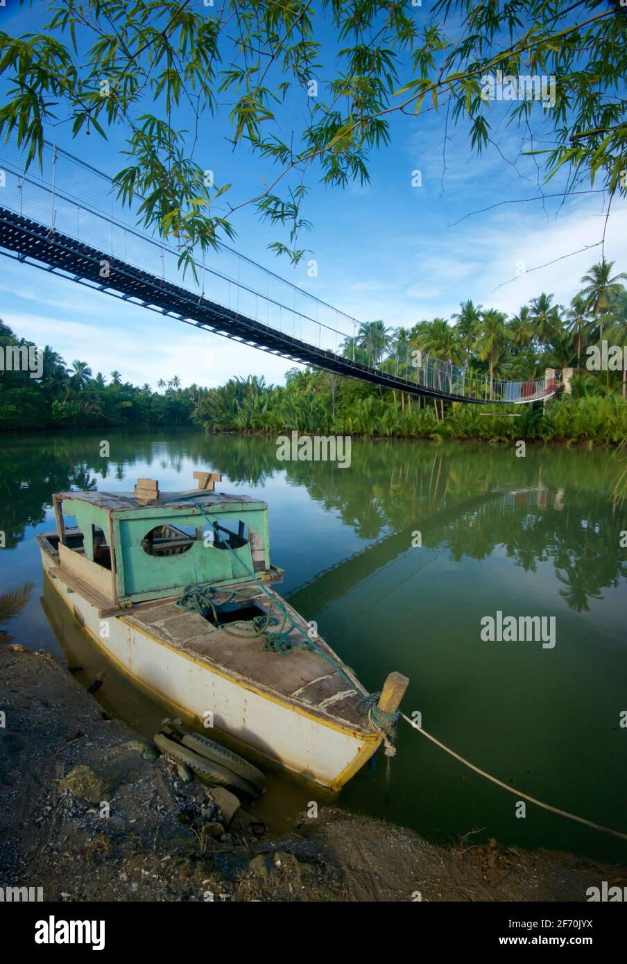 Moored boats beneath a suspension footbridge on the Loboc River, Bohol ...
