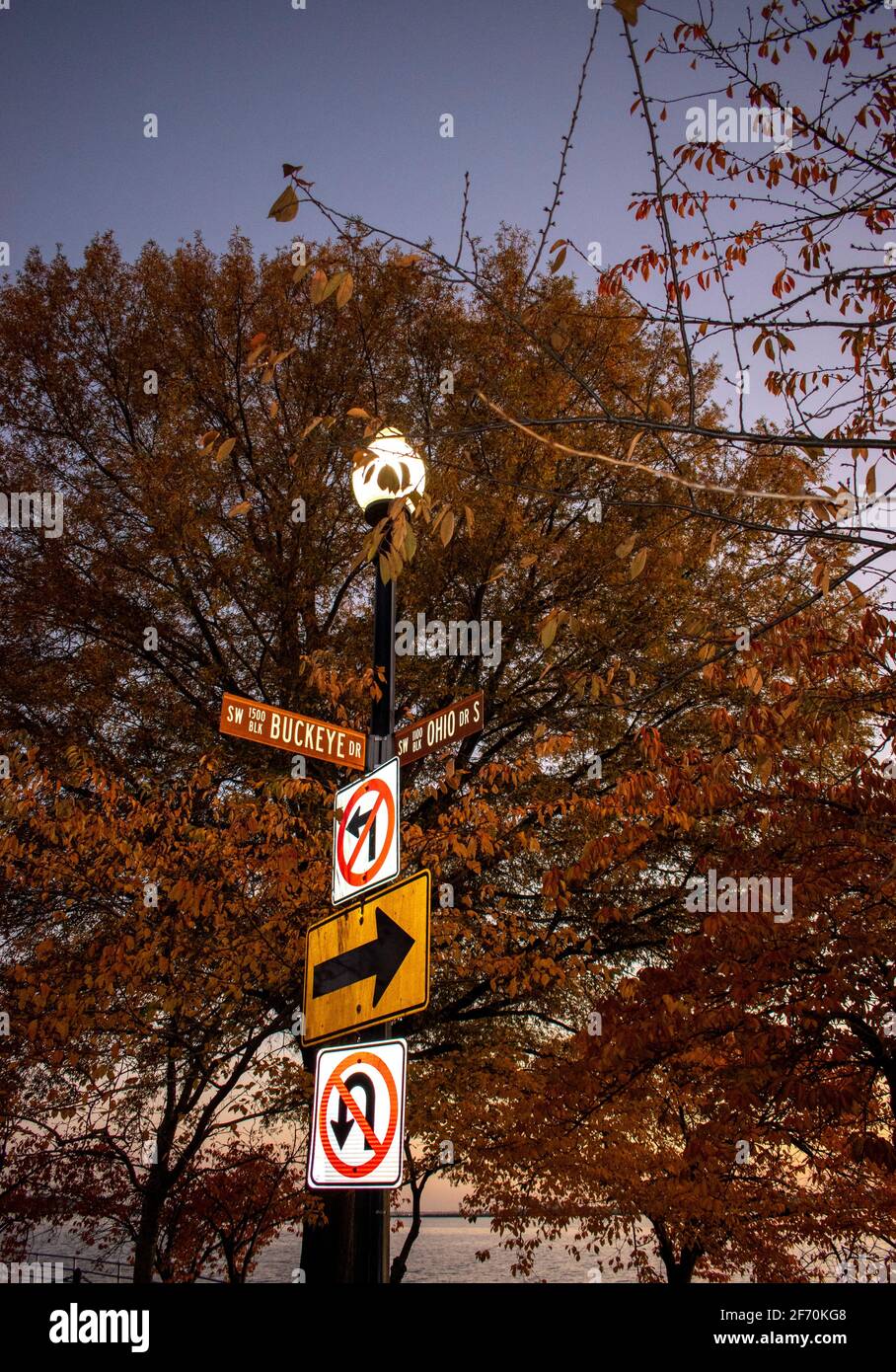 traffic signs on a street lamp in the middle of the road at dusk Stock ...
