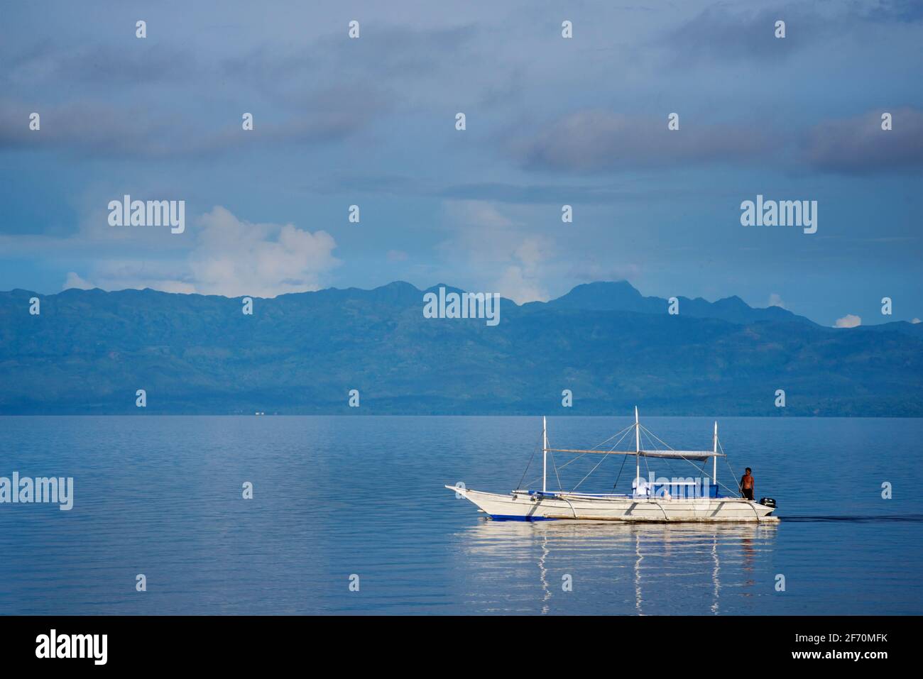 Filipino fisherman in his small outrigger canoe in the Visayan Sea off ...
