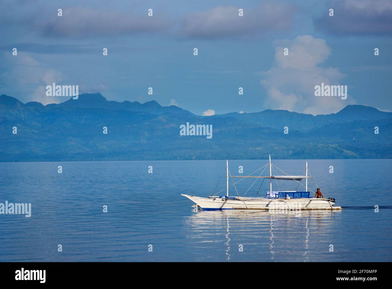 Filipino fisherman in his small outrigger canoe in the Visayan Sea off ...