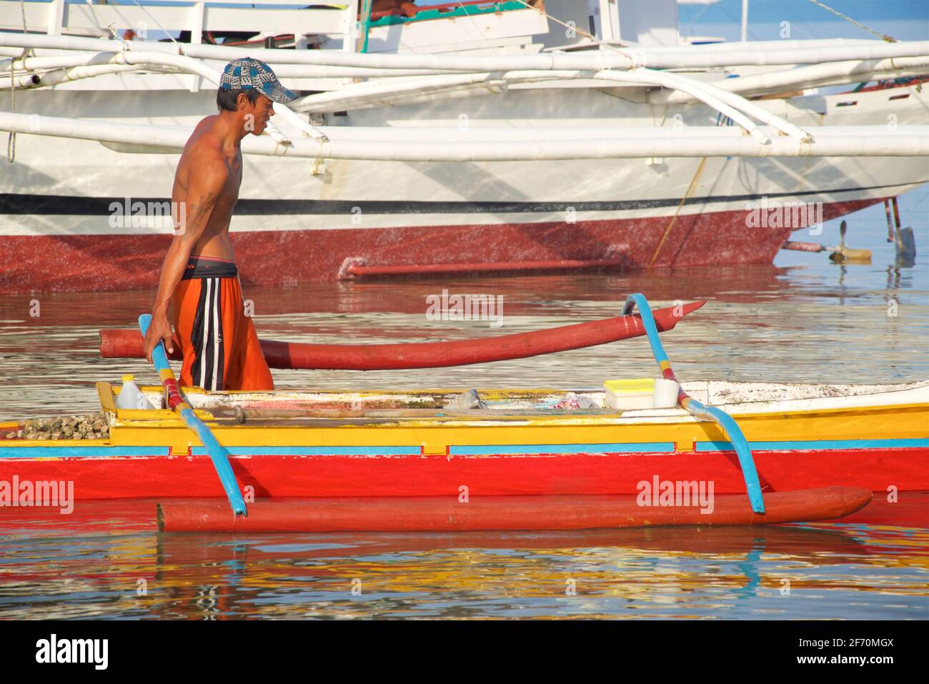 Filipino fisherman prepares to take his outrigger canoe out to fish in ...