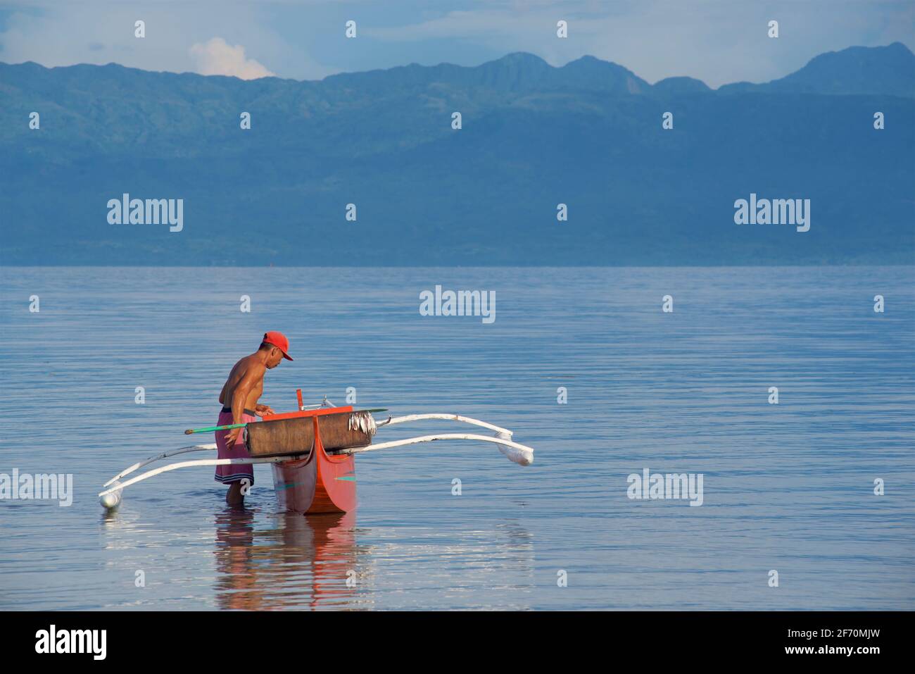 Filipino fisherman prepares to take his outrigger canoe out to fish in ...