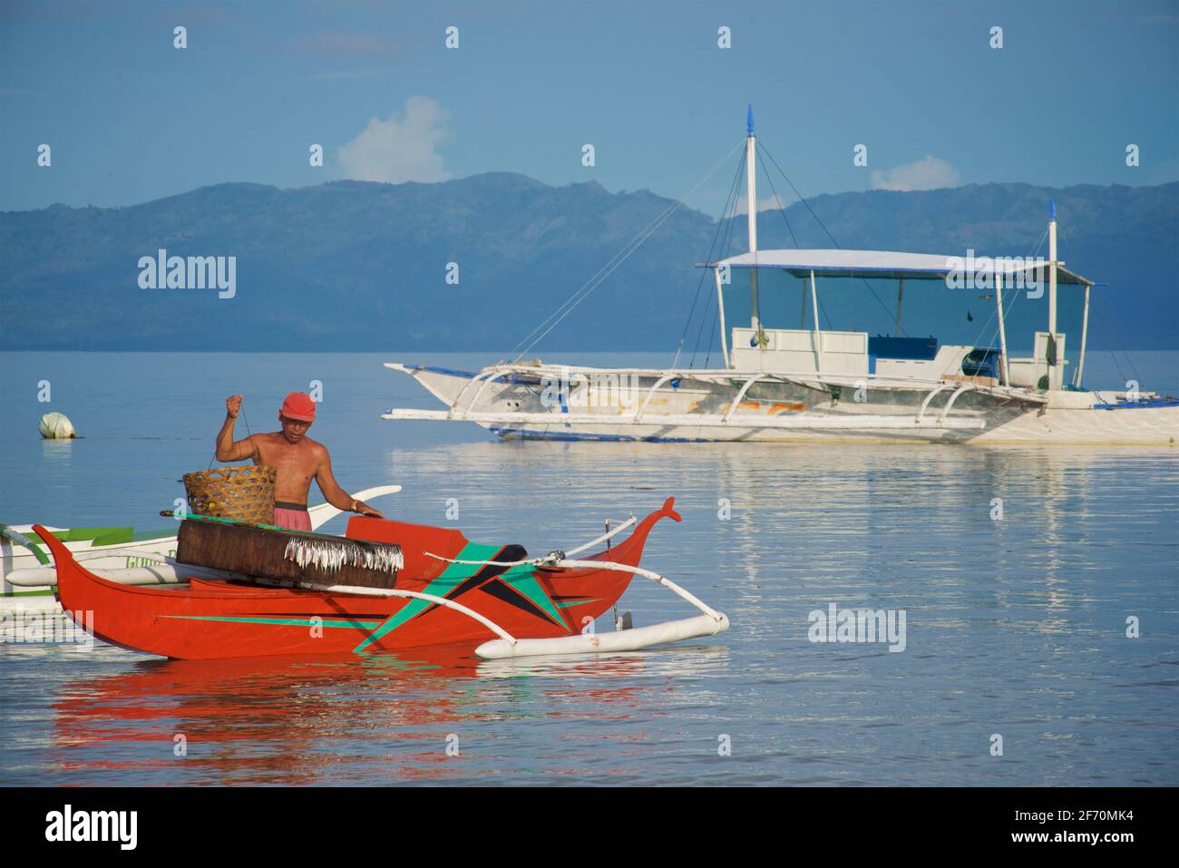 Filipino fisherman prepares to take his outrigger canoe out to fish in ...