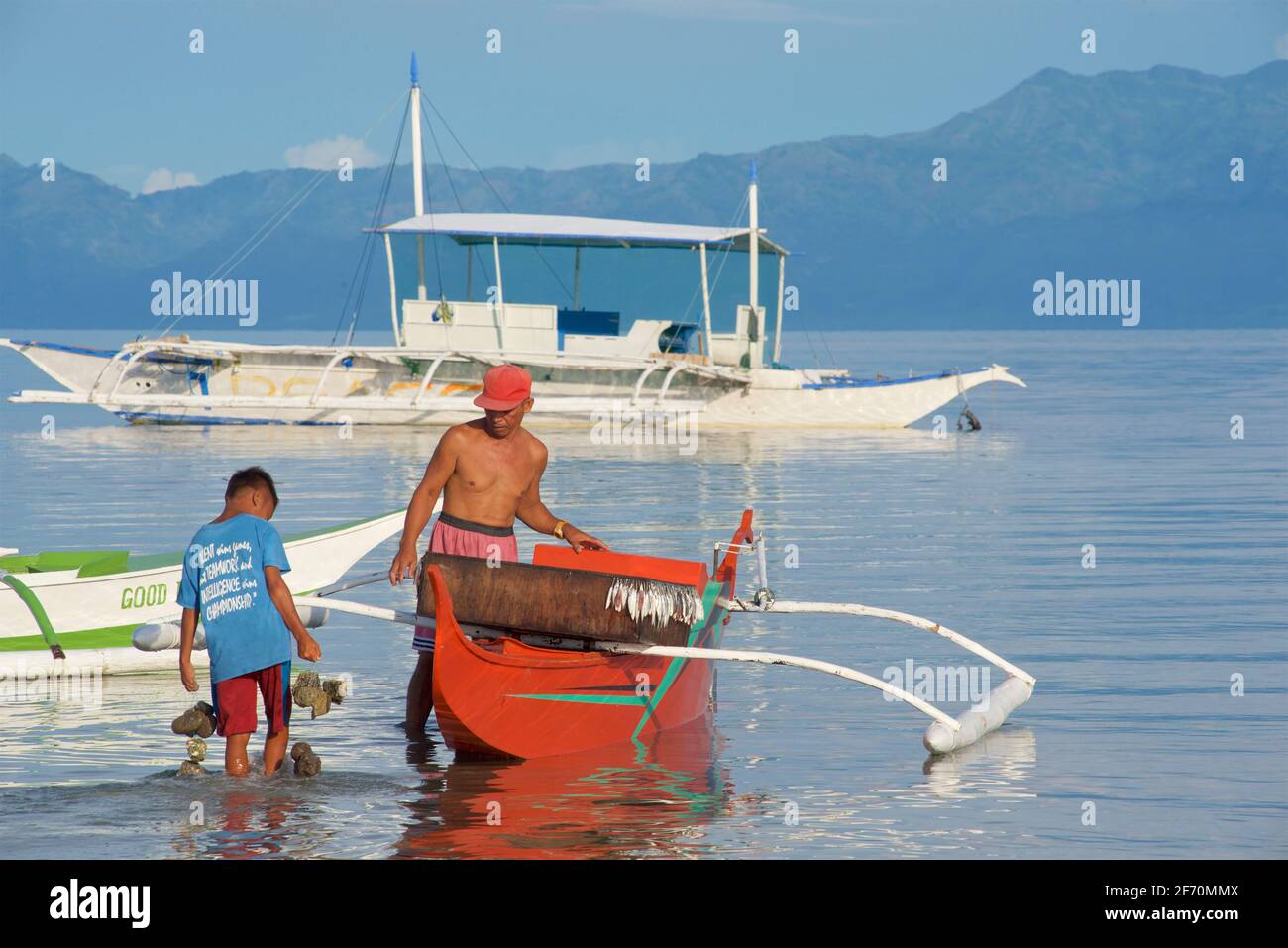 Filipino fisherman prepares to take his outrigger canoe out to fish in ...