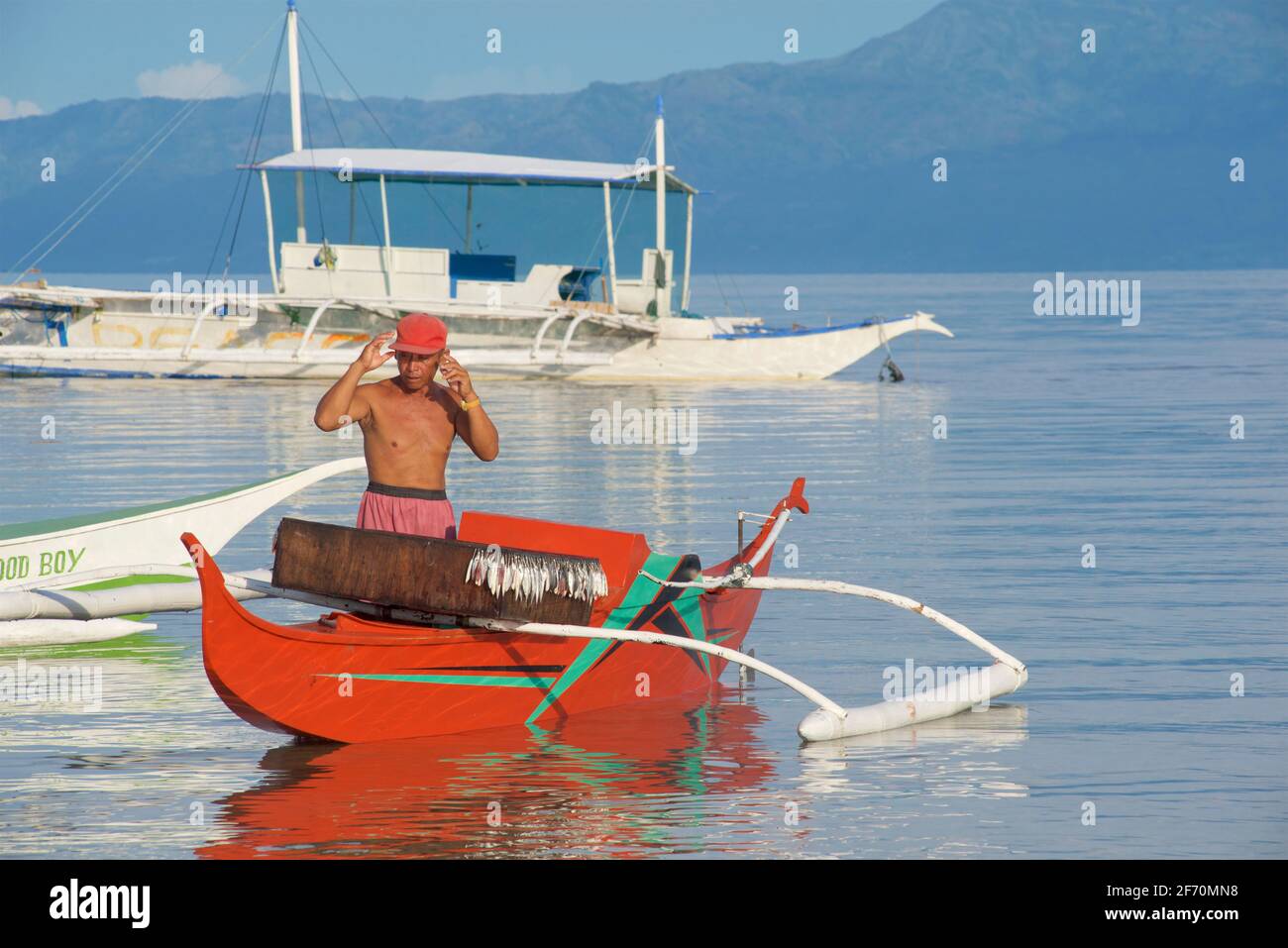 Filipino fisherman prepares to take his outrigger canoe out to fish in ...
