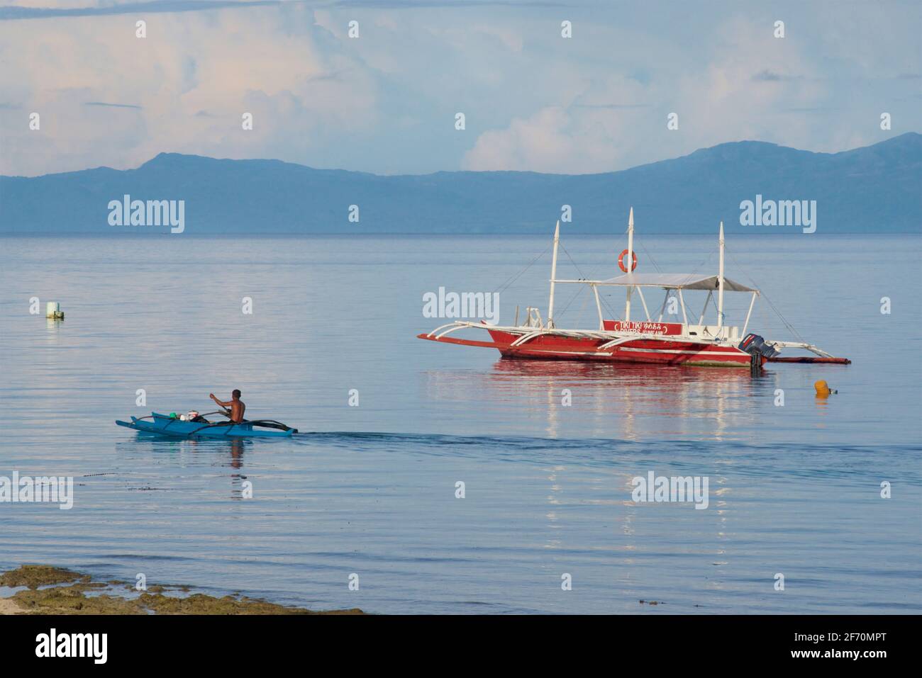 Filipino fisherman in his small outrigger canoe in the Visayan Sea off ...