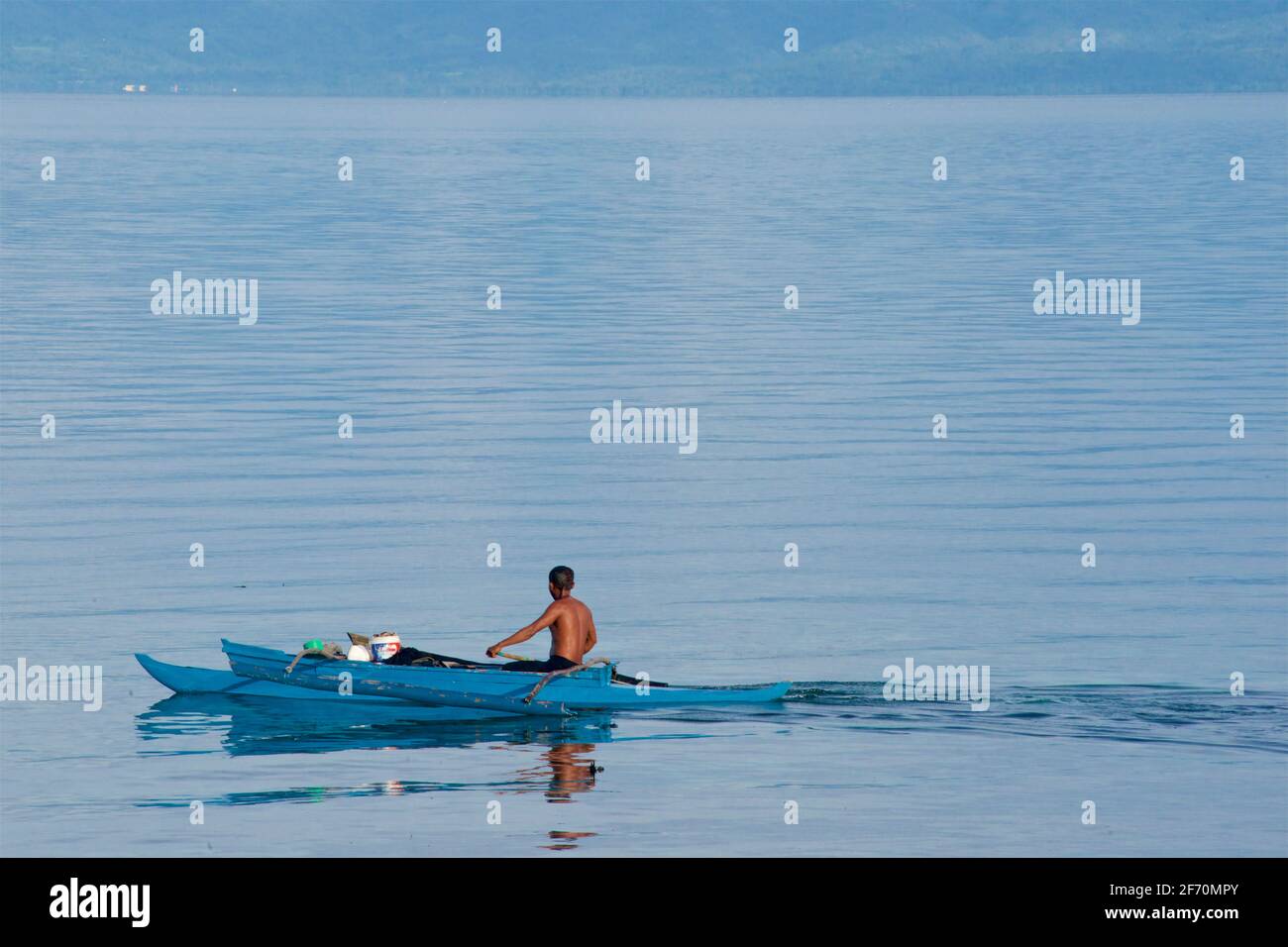 Filipino fisherman in his small outrigger canoe in the Visayan Sea off ...