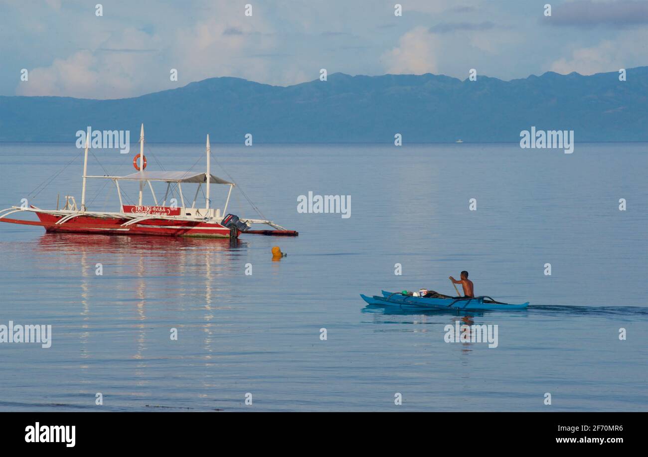 Filipino fisherman in his small outrigger canoe in the Visayan Sea off ...