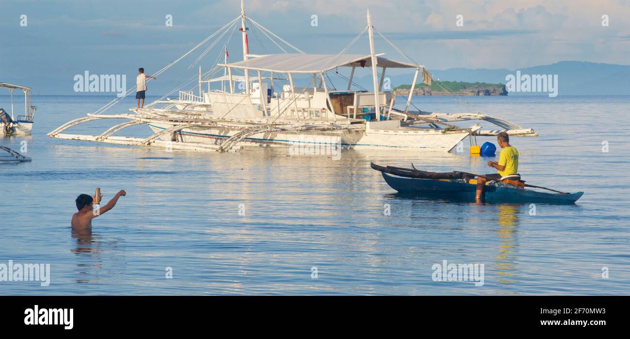 Filipino fisherman in his small outrigger canoe in the Visayan Sea off ...