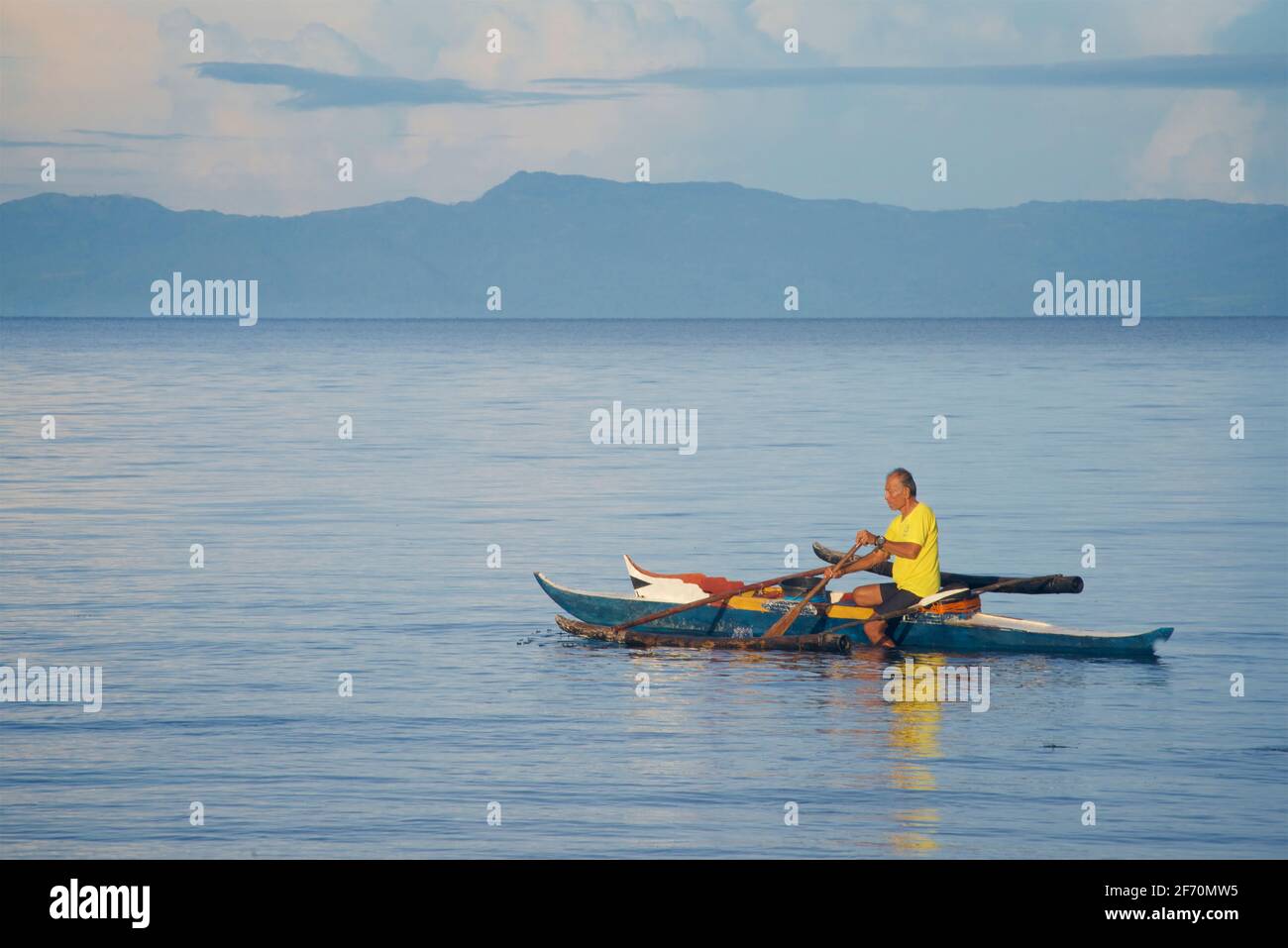 Filipino fisherman in his small outrigger canoe in the Visayan Sea off ...