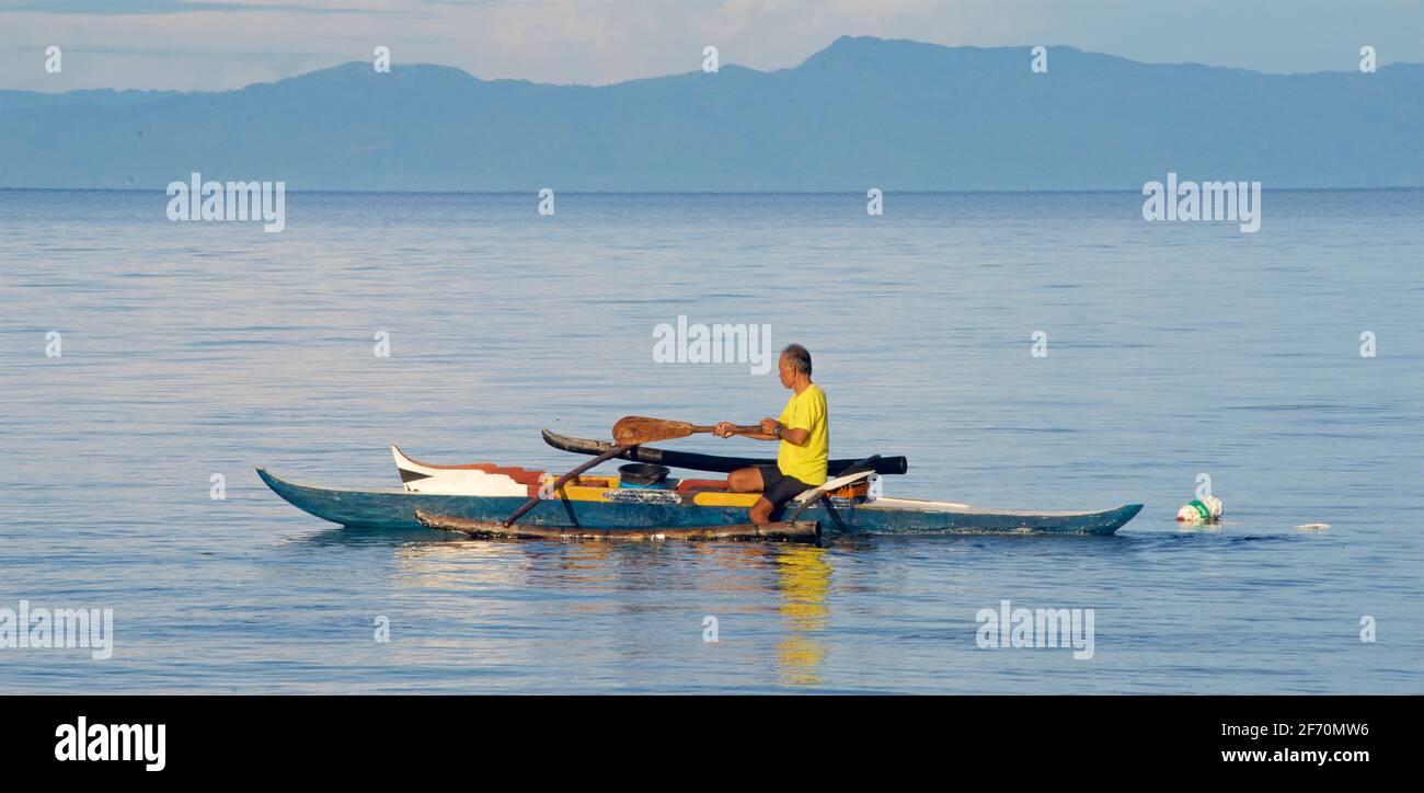 Filipino fisherman in his small outrigger canoe in the Visayan Sea off ...