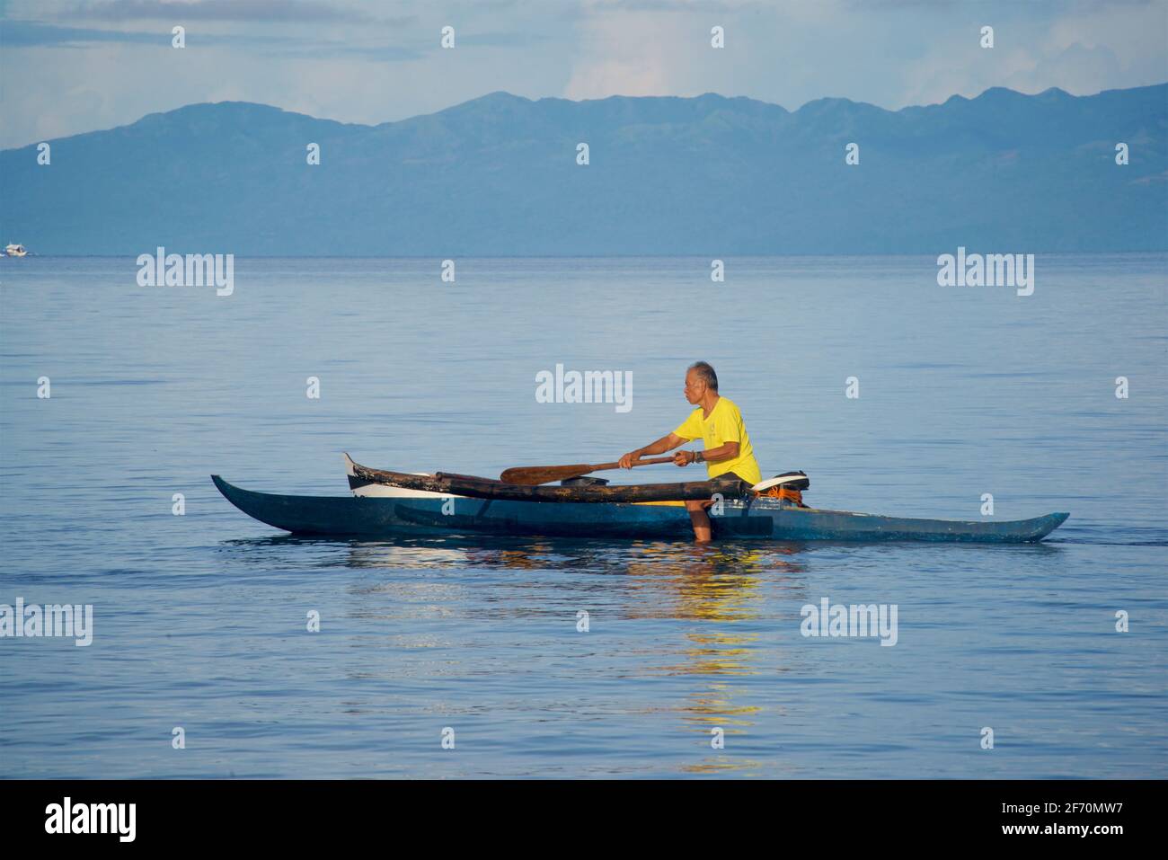 Filipino fisherman in his small outrigger canoe in the Visayan Sea off ...