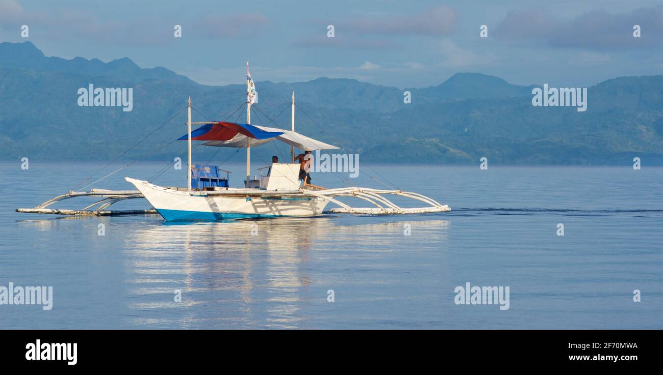 Filipino fisherman in his small outrigger canoe in the Visayan Sea off ...