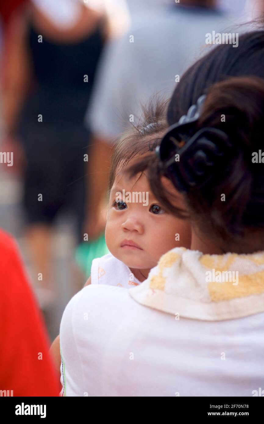 Filipina mother carrying her baby in a procession for Flores de Mayo ...