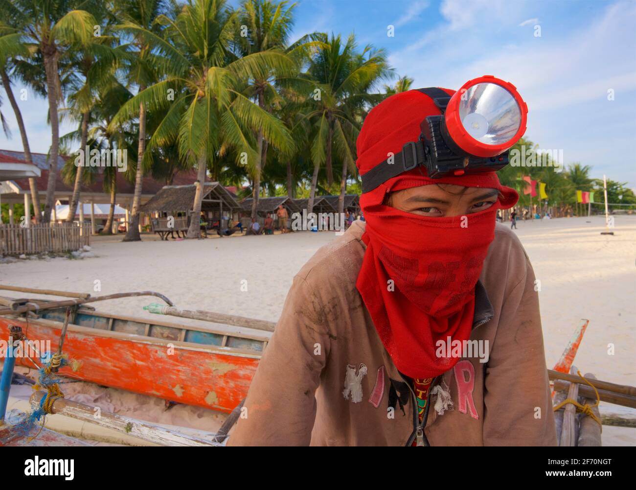 Portrait of a Filipino fisherman in his boat wearing red balaclava and ...
