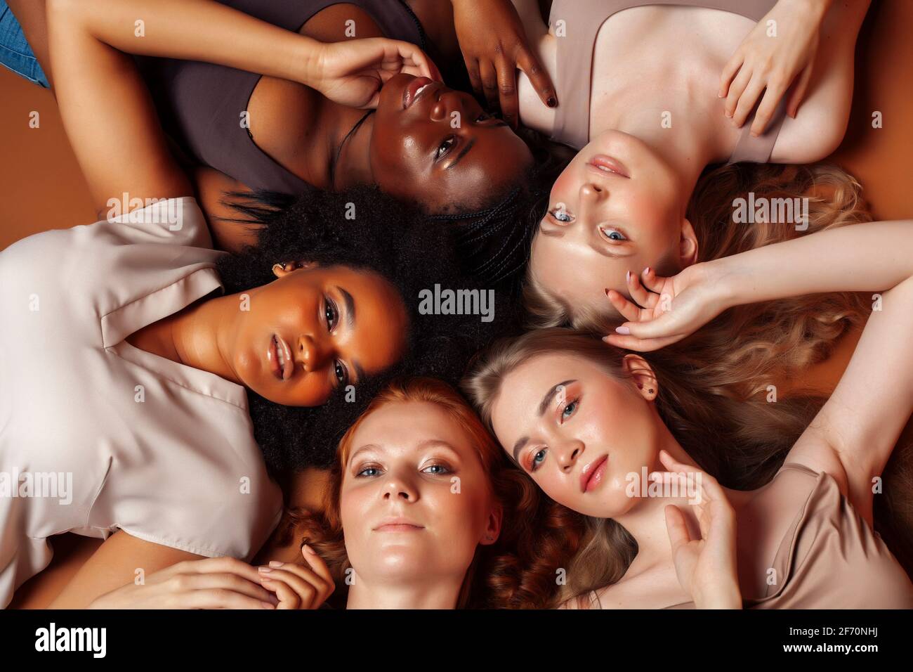 young pretty caucasian, afro, scandinavian woman posing cheerful together on brown background ...