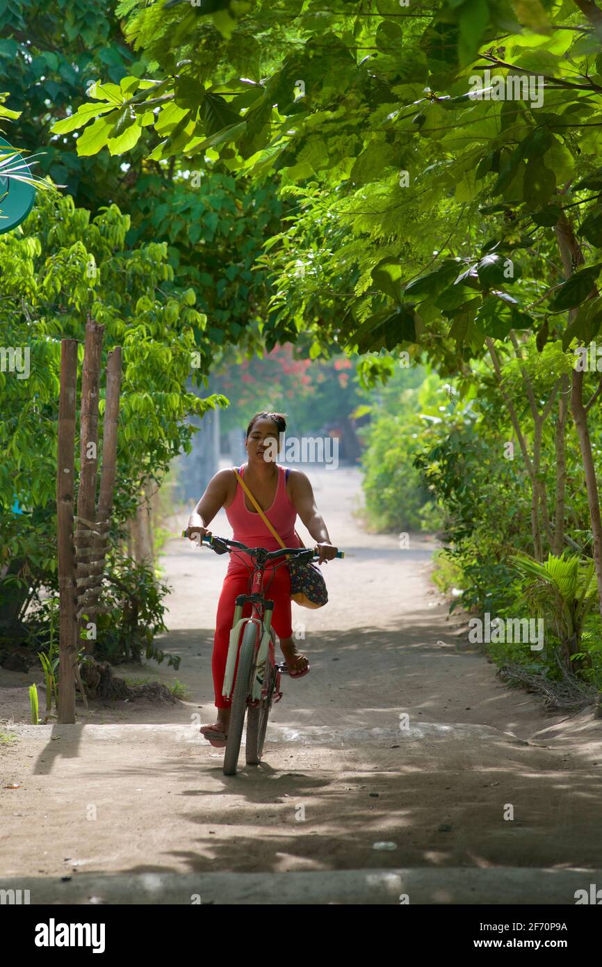 Filipina woman riding her bicycle on the narrow lanes of Malapascua ...