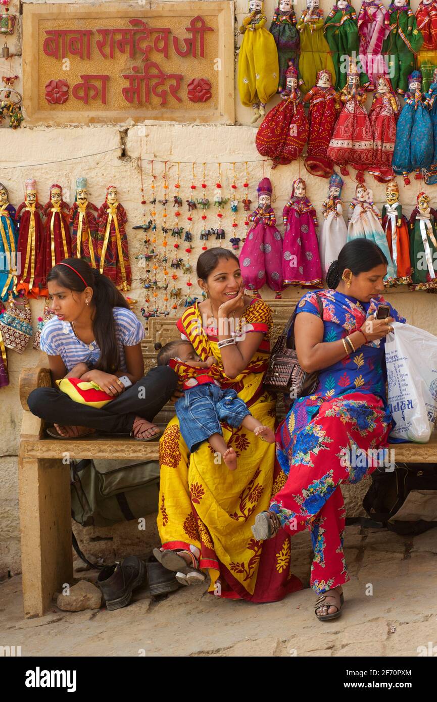 Group of Indian women sitting together on a bench amongst handicrafts ...