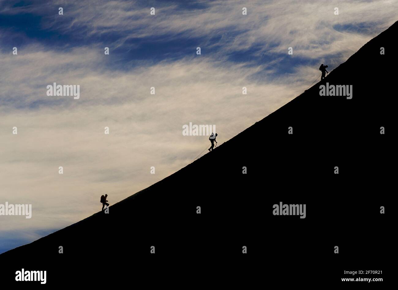 Silhouetted mountaineers climbing up a steep ridge on the Alguile du ...