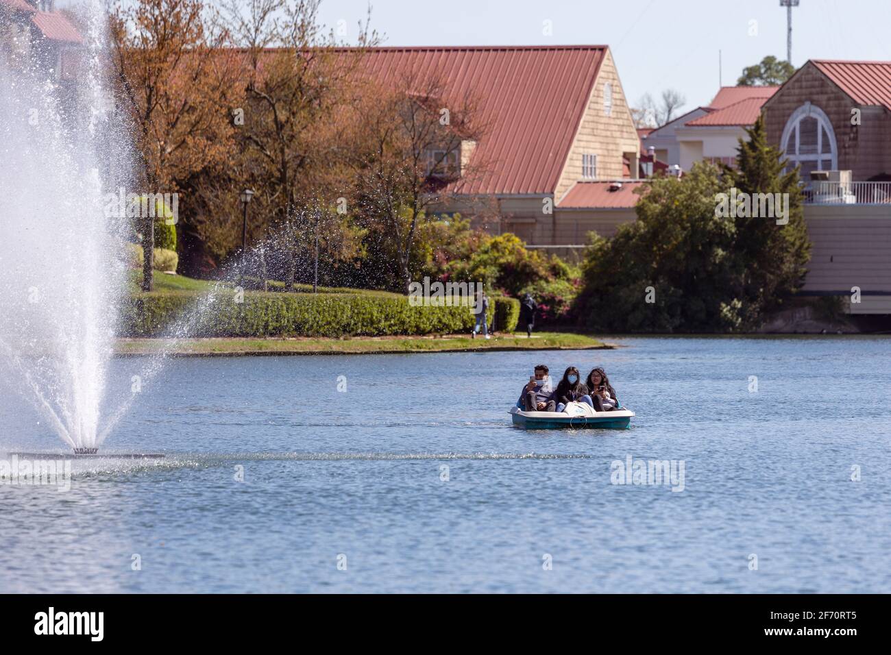 Three teenagers on a paddling boat on a lake enjoying a summers day out ...