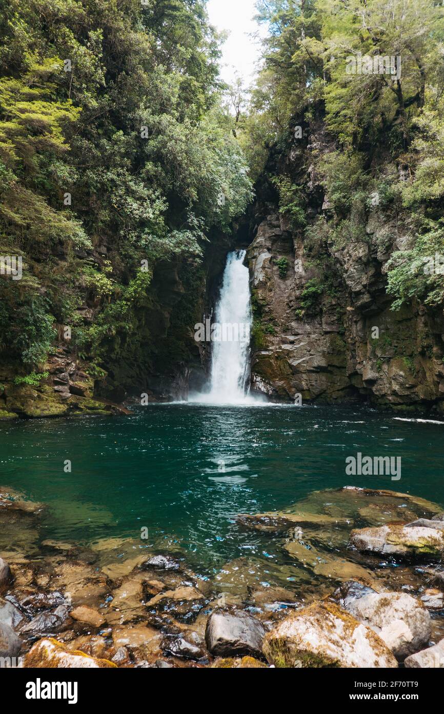 a waterfall cascades into a deep blue pool on the Tauranga-Taupo River ...