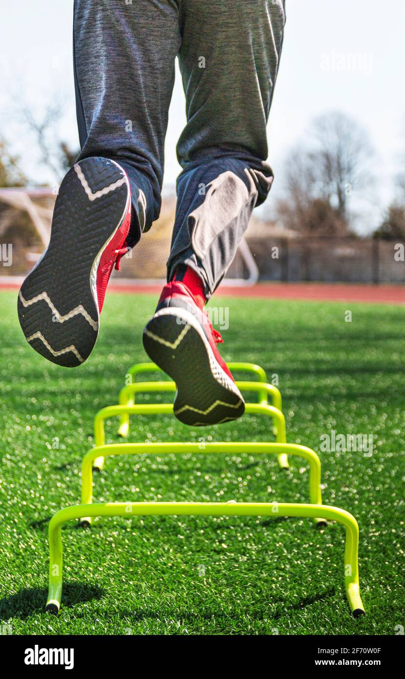 Athlete single leg jumping over six inch yellow mini banana hurdles on a turf field Stock Photo ...