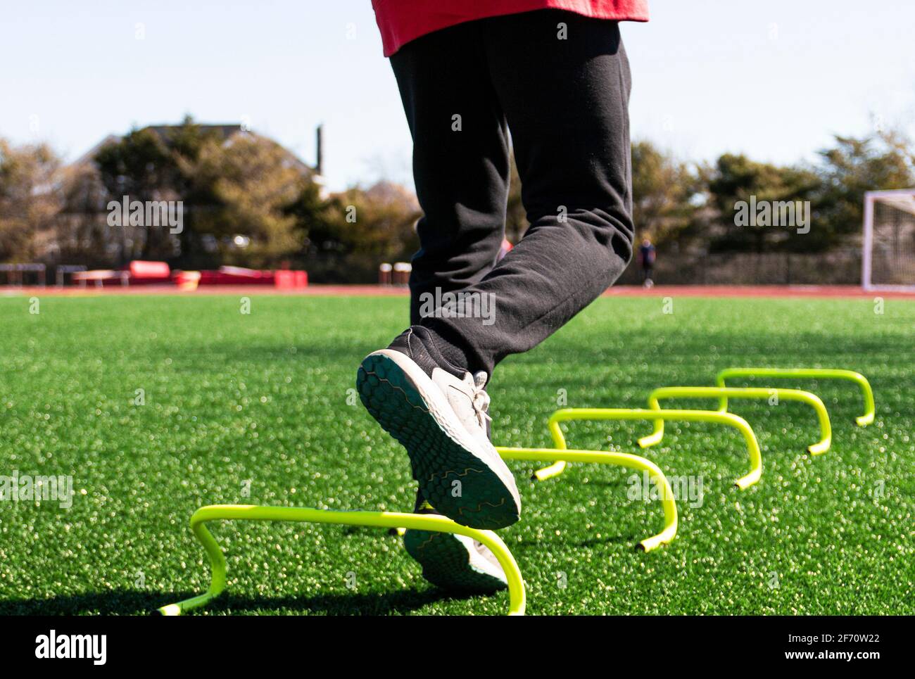 Legs of an athlete jumping over yellow mini banana hurdles on one leg ...