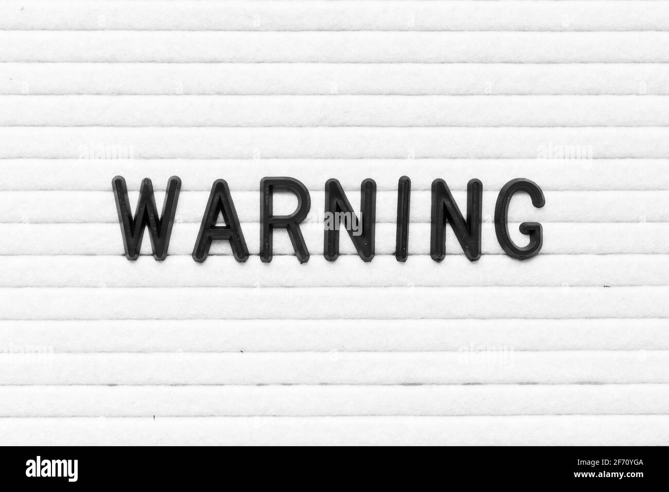 Black color letter in word warning on white felt board background Stock ...