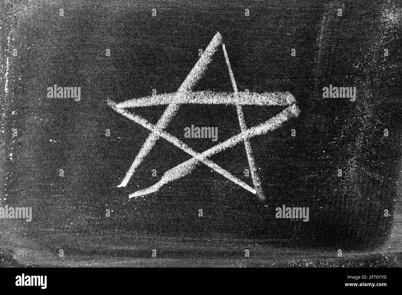 White color chalk hand drawing as star shape on blackboard or ...