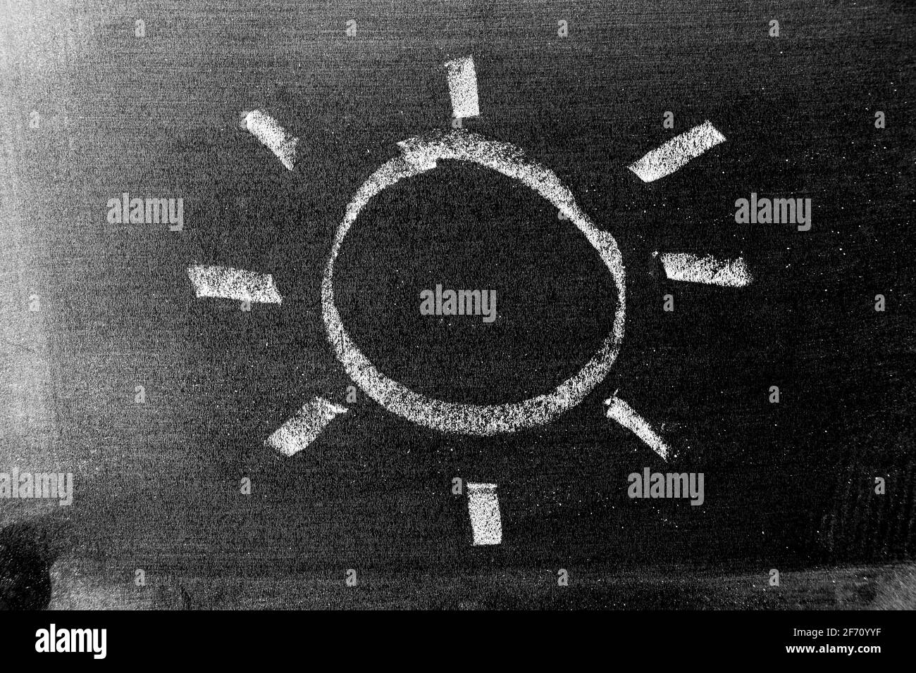 White color chalk hand drawing in sun with ray shape on blackboard or ...
