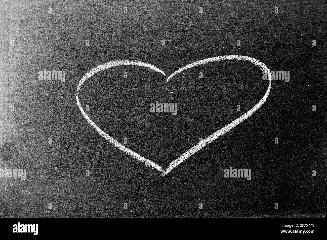 White color chalk hand drawing in heart shape on blackboard or ...