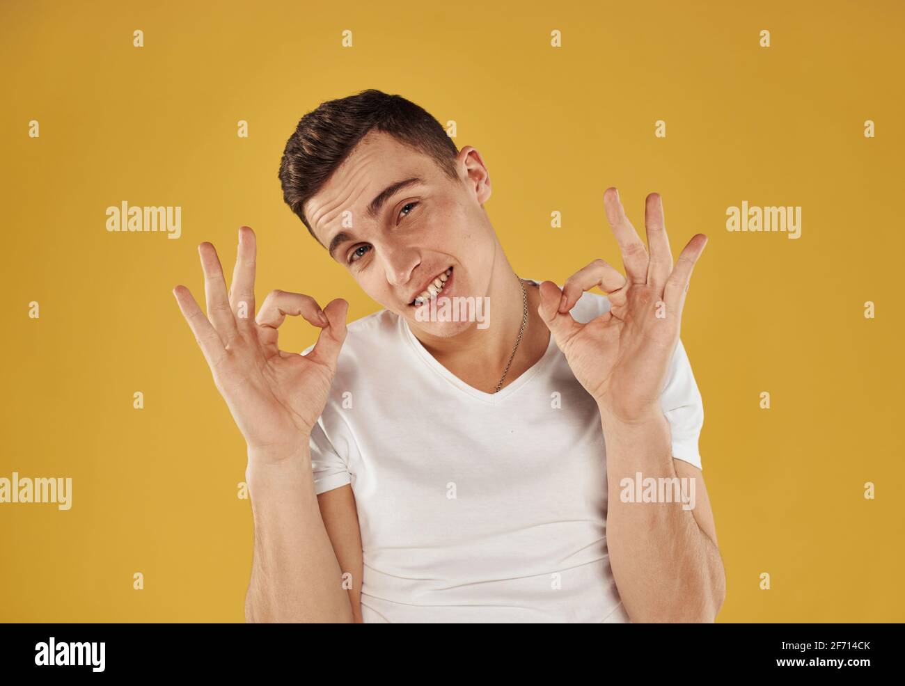 happy brunette man on yellow background shows positive hand gesture Stock Photo - Alamy