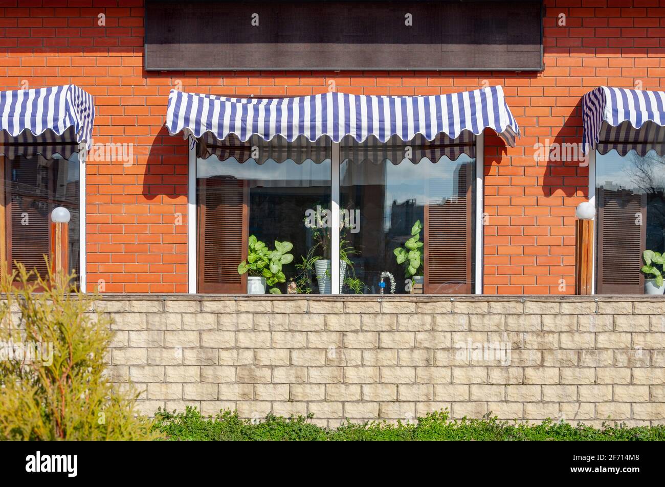 Blue and white stripe awning over glass window. Front outside view of a ...