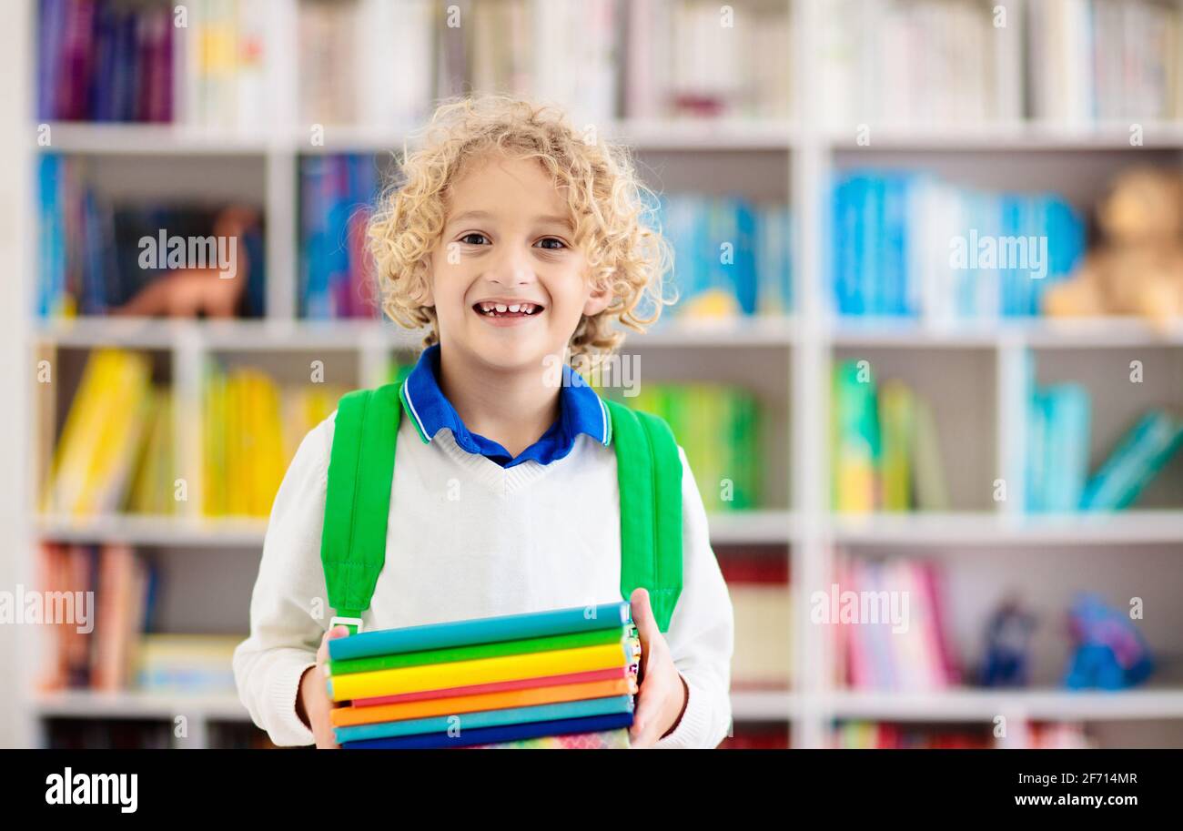 Child reading book. Kids read. Little boy at a colorful bookshelf doing ...