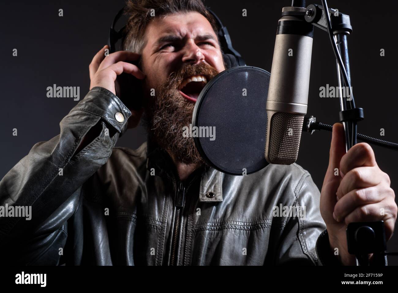 Man with microphone singing song. Musician in music hall. Funny guy ...
