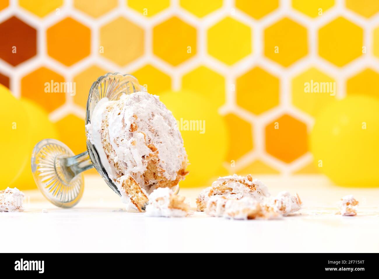 A broken cake lying on an overturned stand. Yellow background with a ...