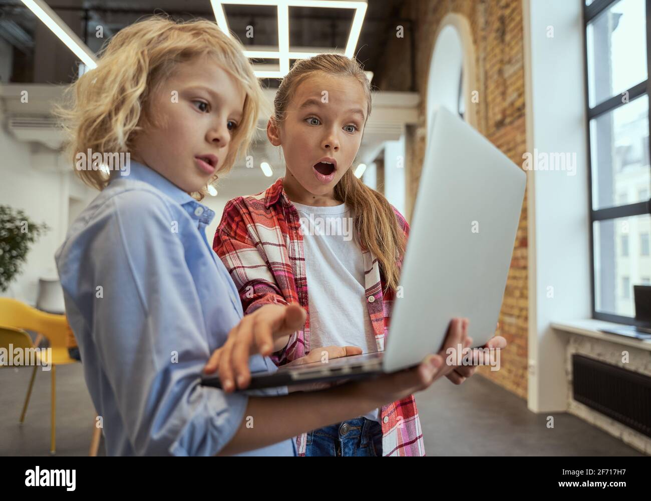 Two curious kids, little boy and girl looking surprised while using ...