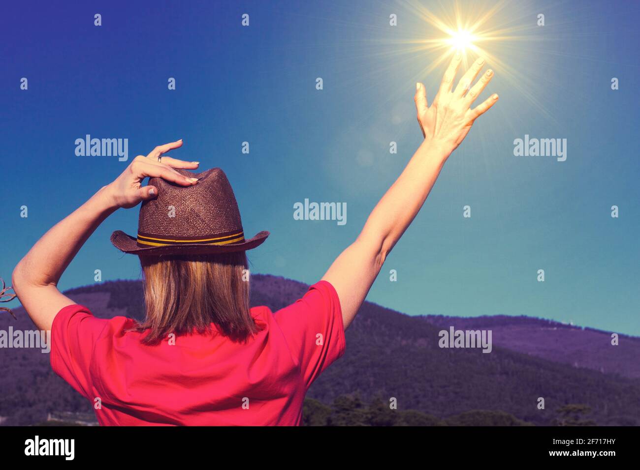 Back view of a woman in a clear windy day, wearing a hat, gesture of ...