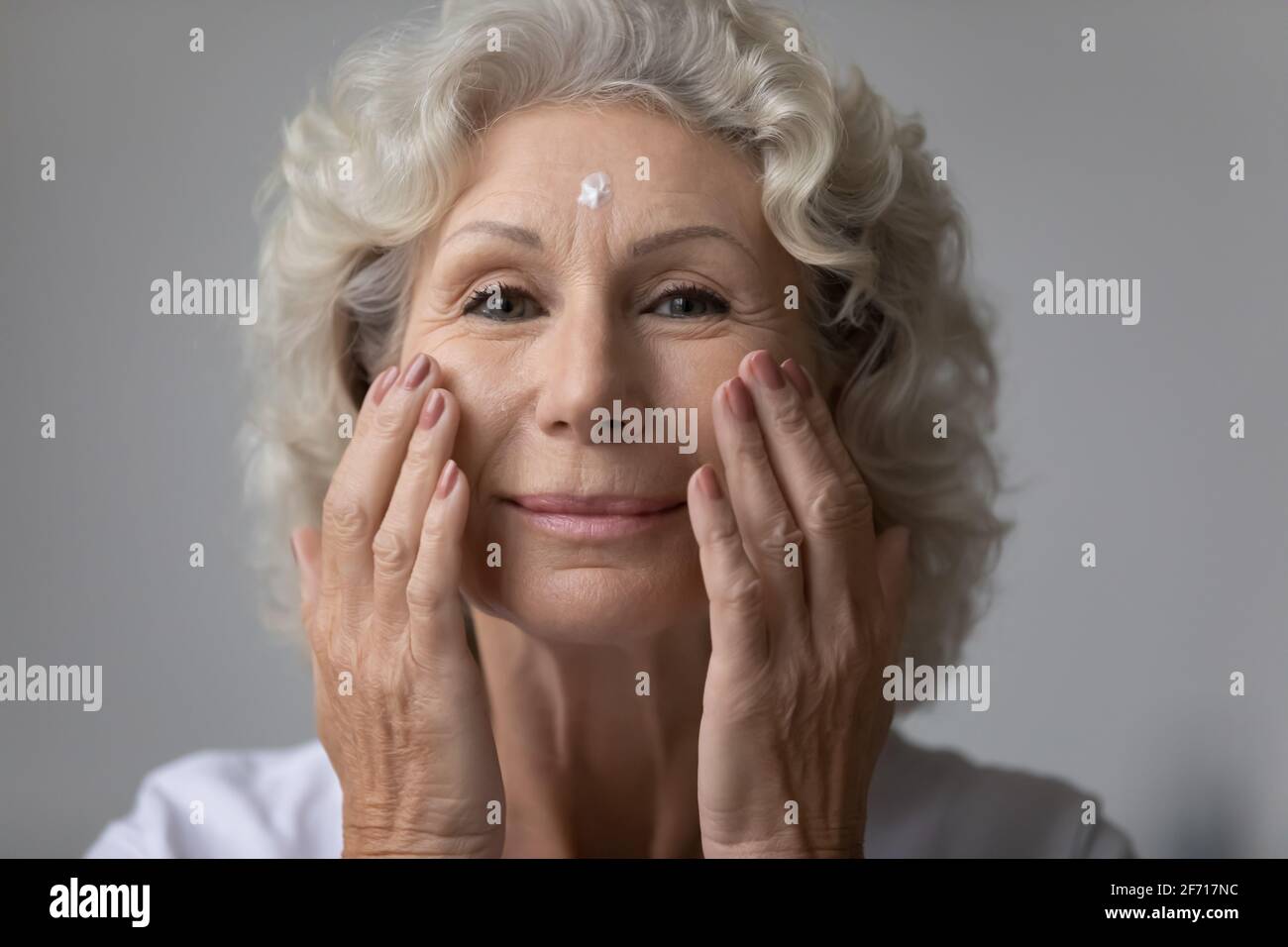 Portrait of happy mature lady applying moisturizing cream Stock Photo ...