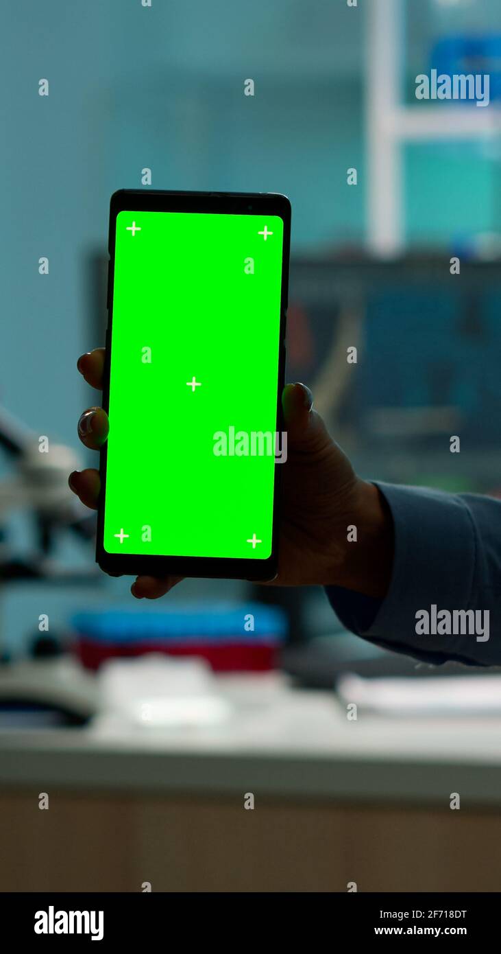 Close up of chemist's hand holding smartphone with green screen ...